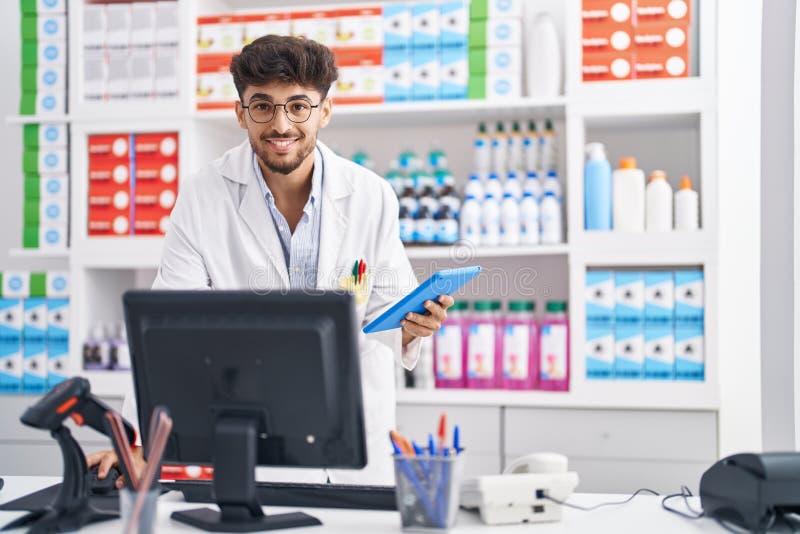 Young Arab Man Pharmacist Using Computer and Touchpad at Pharmacy Stock ...