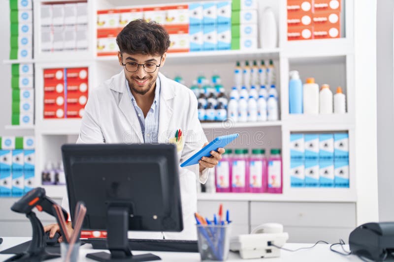 Young Arab Man Pharmacist Using Computer and Touchpad at Pharmacy Stock ...