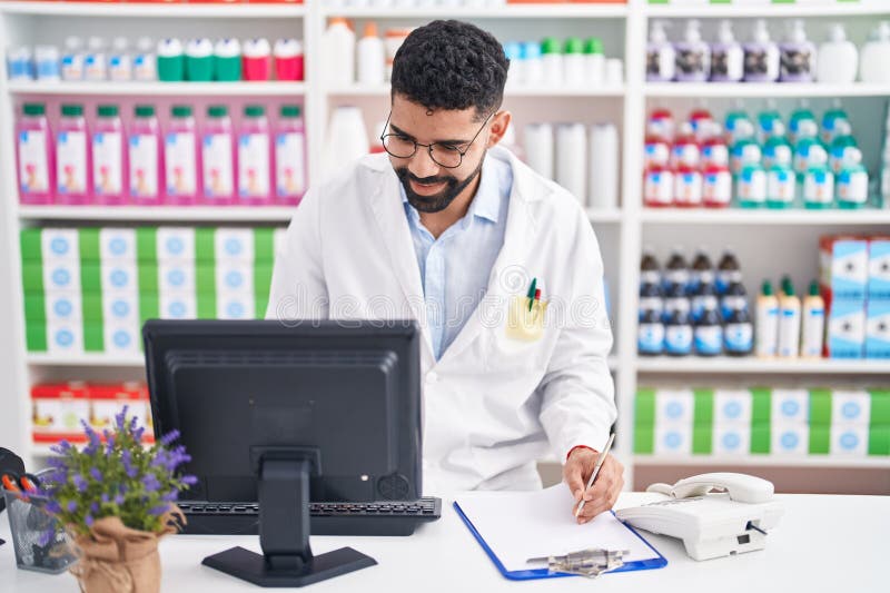 Young Arab Man Pharmacist Using Computer Writing on Document at ...