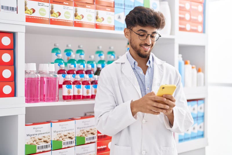 Young Arab Man Pharmacist Using Smartphone Standing at Pharmacy Stock ...
