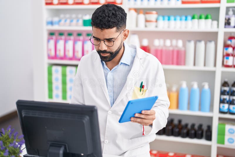 Young Arab Man Pharmacist Using Touchpad and Computer at Pharmacy Stock ...