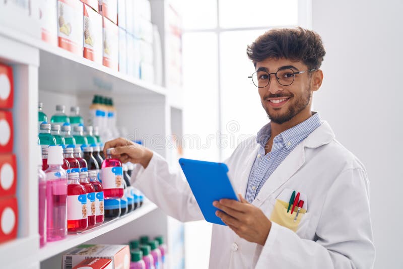 Young Arab Man Pharmacist Using Touchpad Holding Medicine Bottle at ...