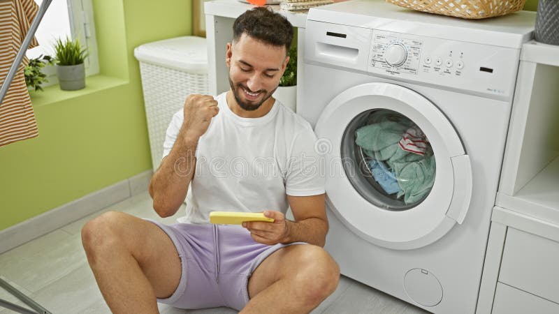 Young Arab Man Playing Video Game Waiting for Washing Machine at ...