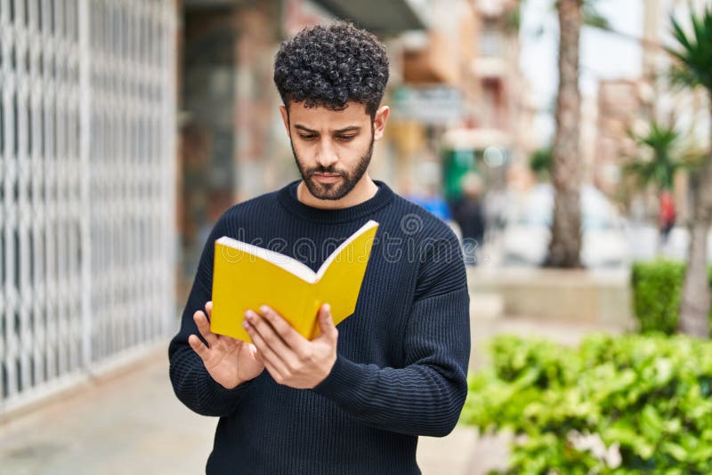 Young Arab Man with Relaxed Expression Reading Book at Street Stock ...