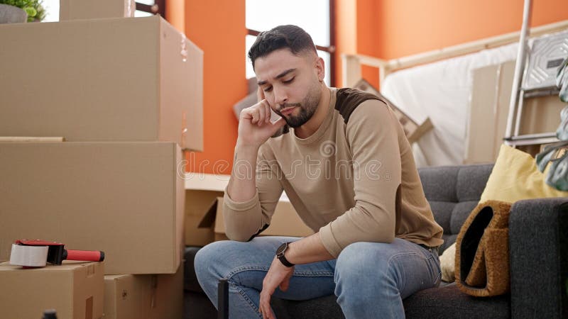 Young Arab Man Sitting on Sofa with Doubt Expression at New Home Stock ...