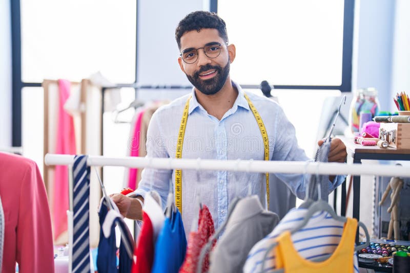 Young Arab Man Tailor Smiling Confident Holding Clothes on Rack at ...