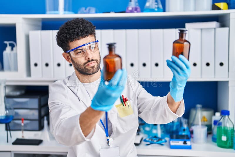 Young Arab Man Wearing Scientist Uniform Holding Bottles at Laboratory ...