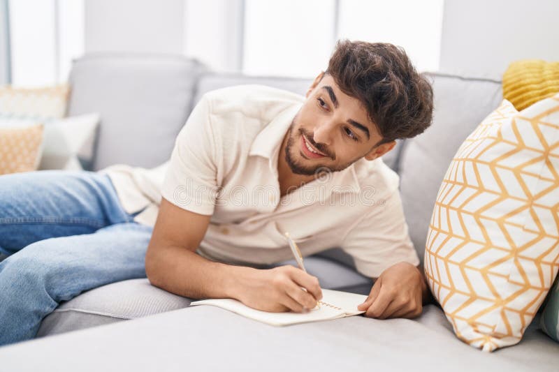 Young Arab Man Writing on Notebook Sitting on Sofa at Home Stock Photo ...