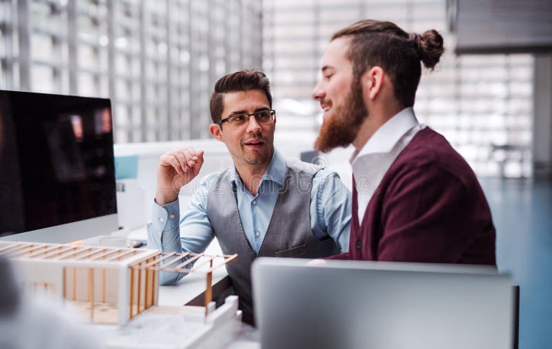 Two Young Architects with Blueprints Standing in Office, Talking. Stock ...
