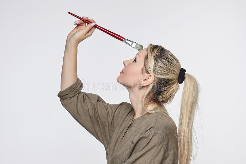 Young Artist Poses in Front of the Camera, Holding a Brush To Her Head ...
