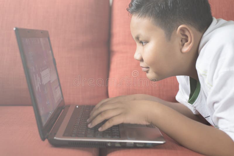 Young Asian Boy Using Laptop Computer on a Sofa at Home. Stock Image ...