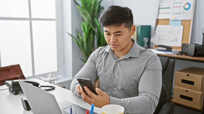 Young Asian Businessman Checking Smartphone at Modern Office Desk Stock ...