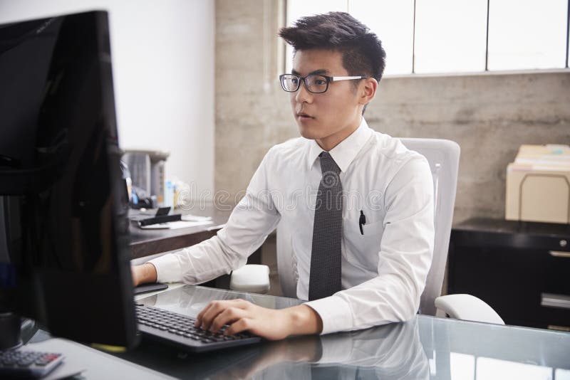 Young Asian Businessman Using a Computer at an Office Desk Stock Image ...
