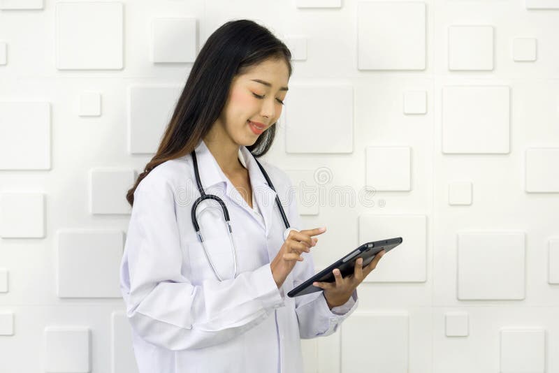 Young Asian Doctor in White Gown and Stethoscope Typing on Tablet ...