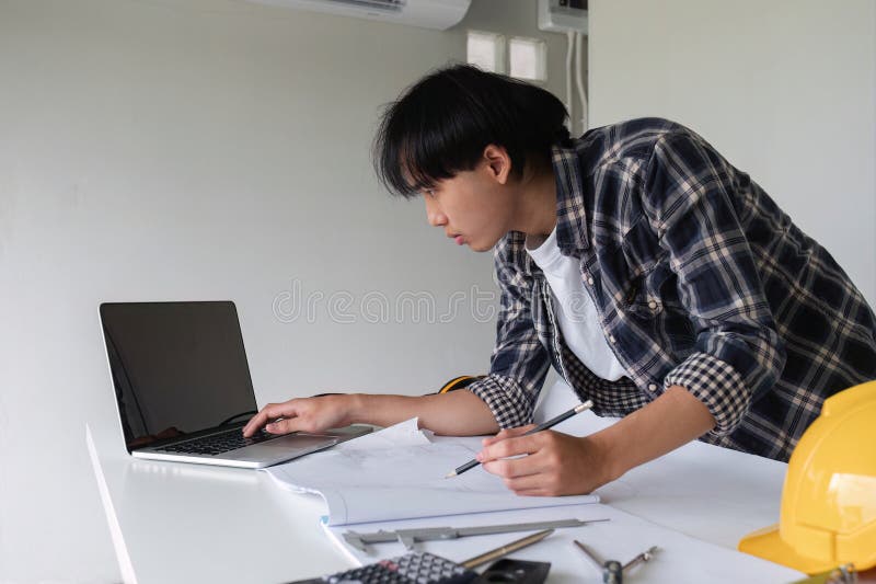 Young Asian Engineer Drawing Construction Project Plans on Plan Paper ...
