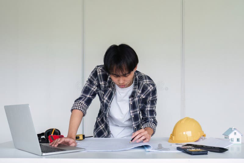 Young Asian Engineer Drawing Construction Project Plans on Plan Paper ...