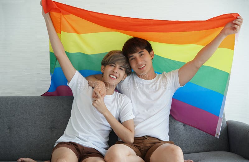 Young Asian Gay Couple Embracing And Holding Rainbow Lgbt Flag Stock