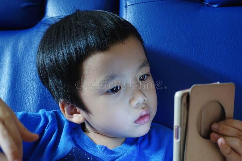 Young Asian Kid Staring at Phone with Blue Background Stock Photo ...