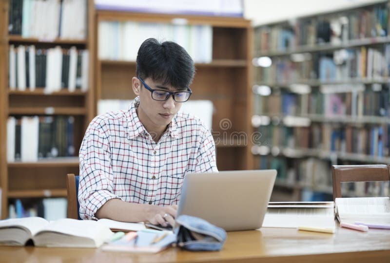 Young Asian Male Sitting Inside a Library Alone Doing Research. Man ...