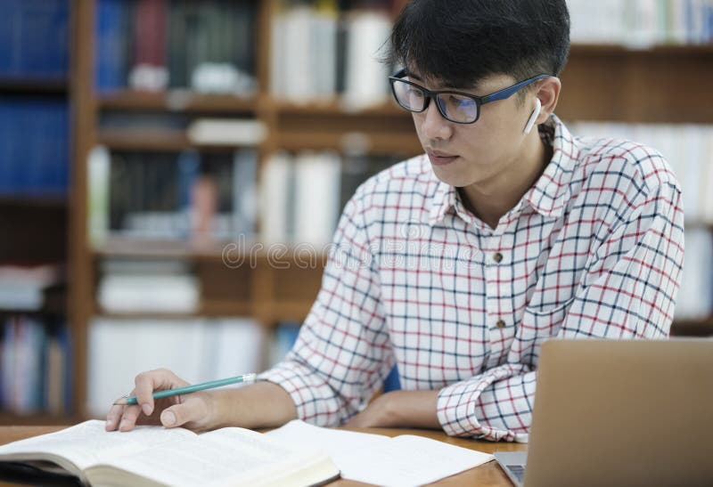 Young Asian Male Sitting Inside a Library Alone Doing Research. Man ...