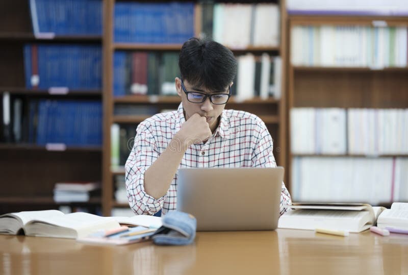 Young Asian Male Sitting Inside a Library Alone Doing Research. Man ...