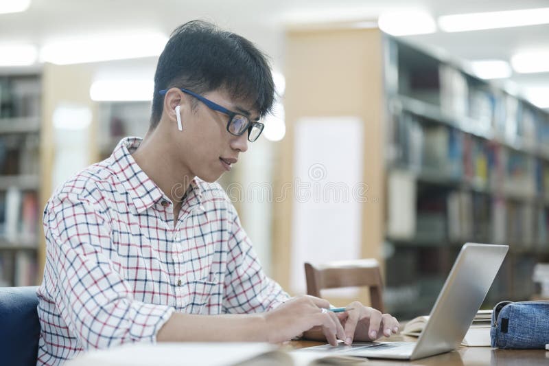 Young Asian Male Sitting Inside a Library Alone Doing Research. Man ...