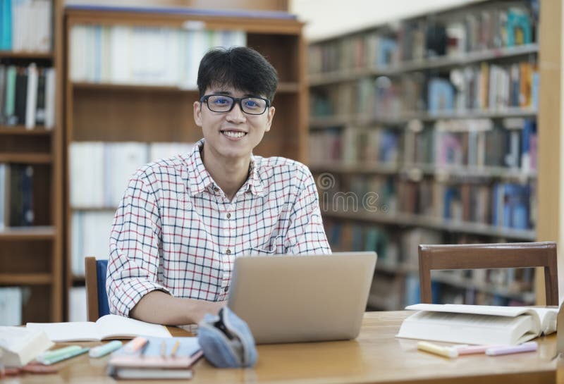 Young Asian Male Sitting Inside a Library Alone Doing Research. Man ...