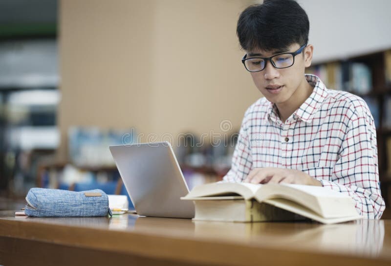 Young Asian Male Sitting Inside a Library Alone Doing Research. Man ...