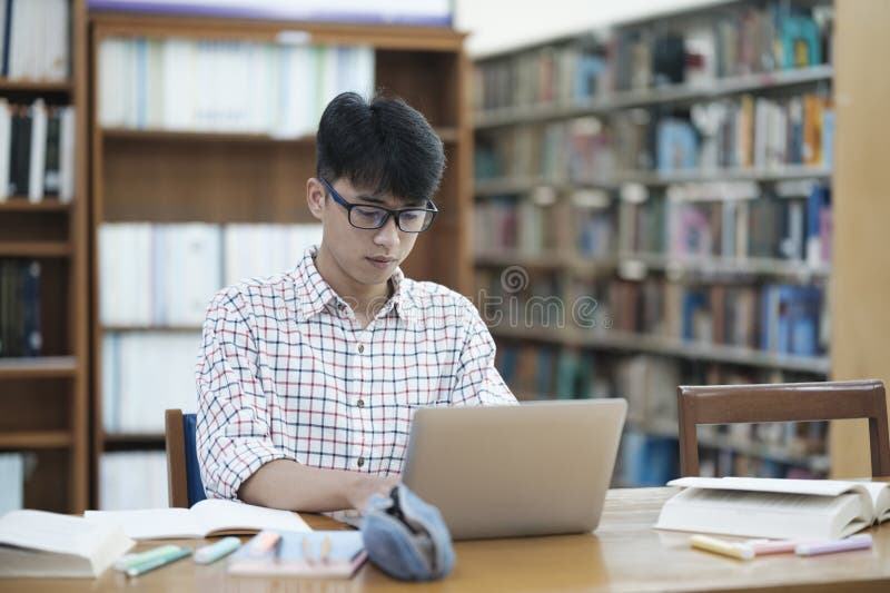 Young Asian Male Sitting Inside a Library Alone Doing Research. Man ...