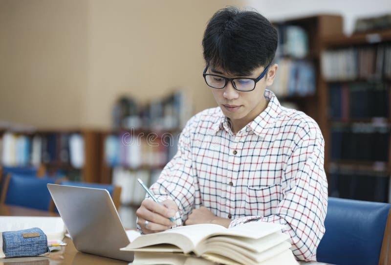 Young Asian Male Sitting Inside a Library Alone Doing Research. Man ...