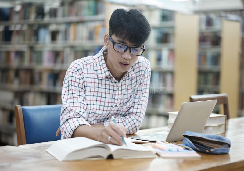Young Asian Male Sitting Inside a Library Alone Doing Research. Man ...