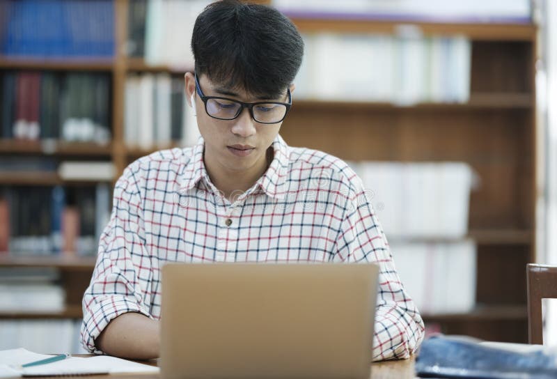 Young Asian Male Sitting Inside a Library Alone Doing Research. Man ...