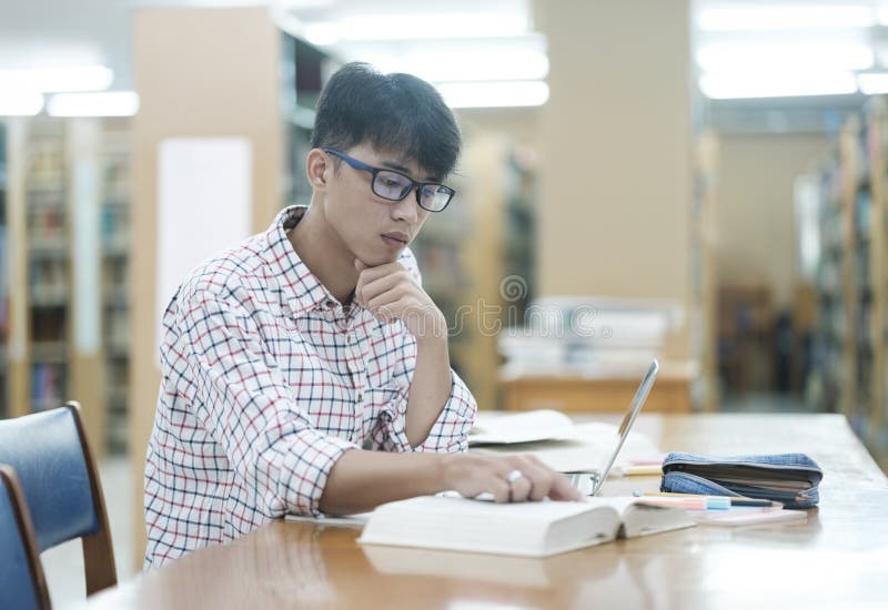 Young Asian Male Sitting Inside a Library Alone Doing Research. Man ...