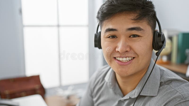 A Young Asian Man with a Headset Smiling in an Office Setting ...