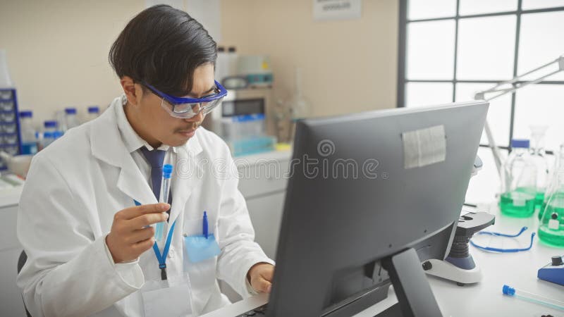 A Young Asian Man in a Lab Coat Conducts Experiments in a Modern ...