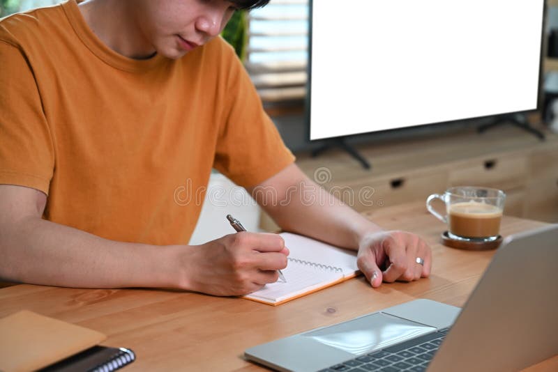 Man Making Notes on Notebook and Using Laptop Computer at Home. Stock ...