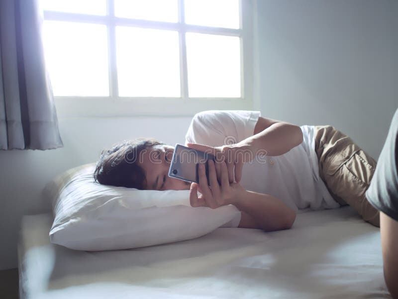 Young Asian Man with Mobile Smart Phone Lying Down on the Bed Stock ...