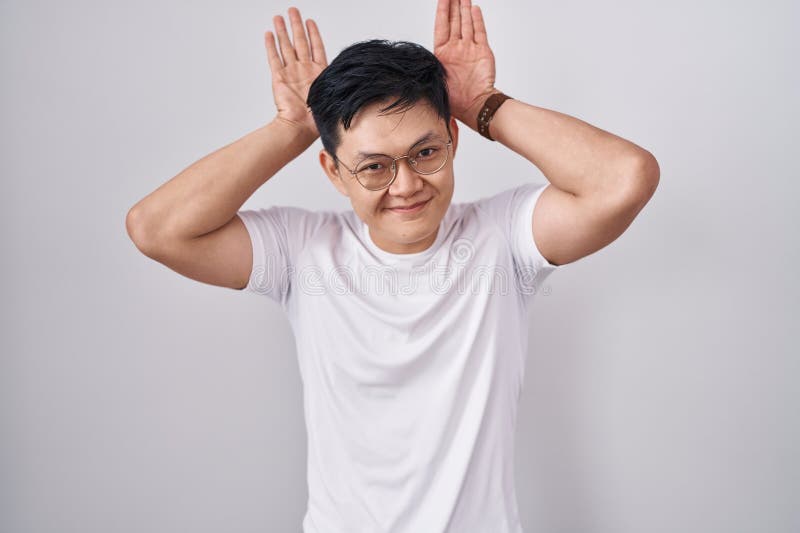Young Asian Man Standing Over White Background Doing Bunny Ears Gesture ...