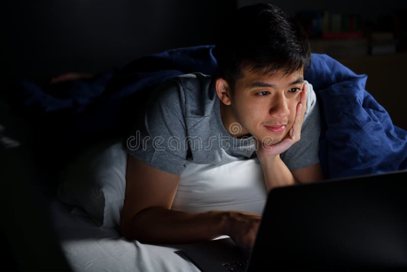 Young Asian Man Using a Laptop in His Bed at Night Stock Photo - Image ...