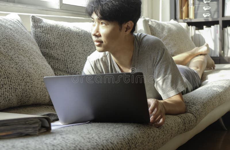 Young Asian Man Work Form Home Using Laptop on Sofa Stock Photo - Image ...