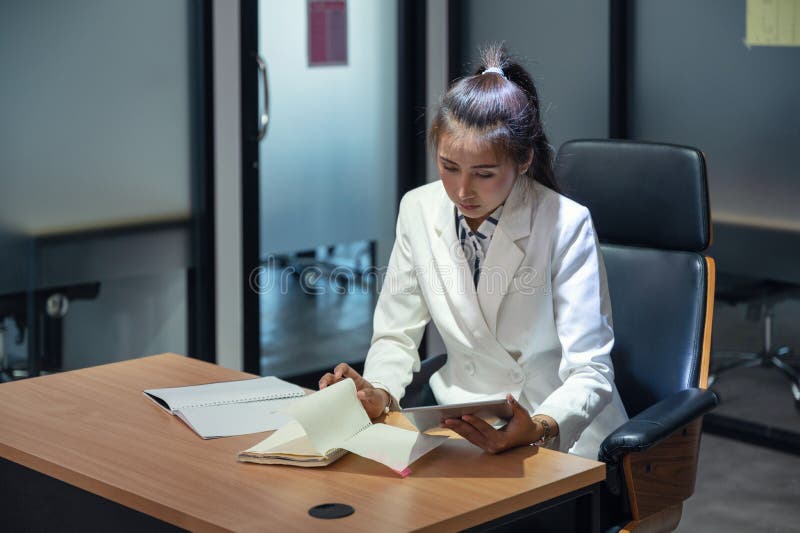 Young Asian Manager Woman Reading and Checking a Notebook with Tablet ...