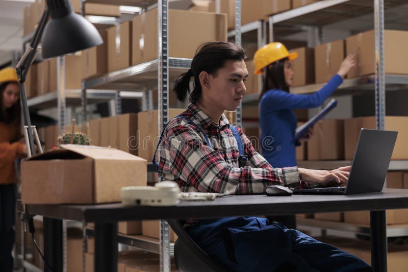 Young Asian Warehouse Supervisor Using Laptop in Storage Room Stock ...