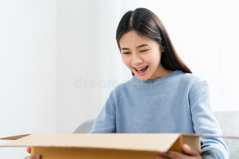 Young Asian Woman Open Box Parcel while Sitting on Sofa. Stock Image ...