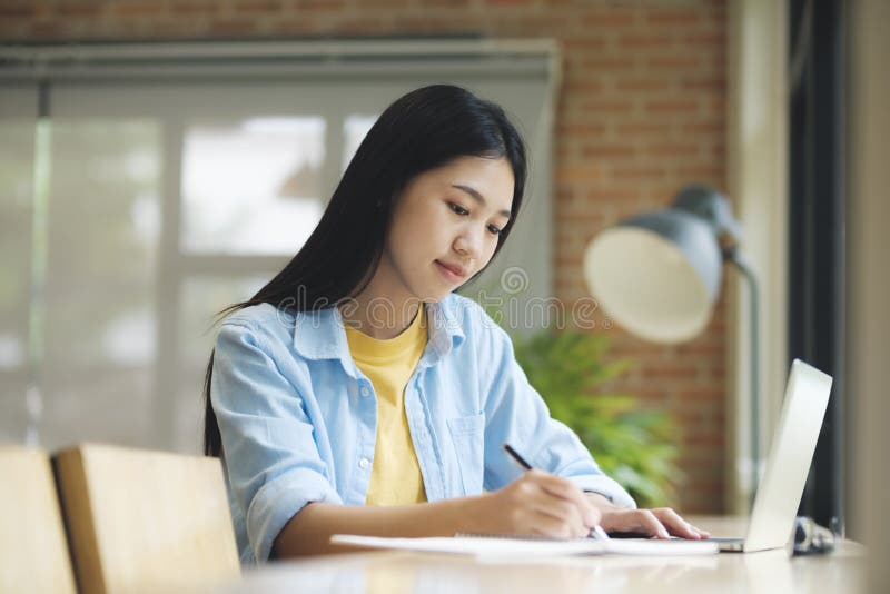 Young Asian Woman Sitting at Table Studying and Writing on Notebook ...