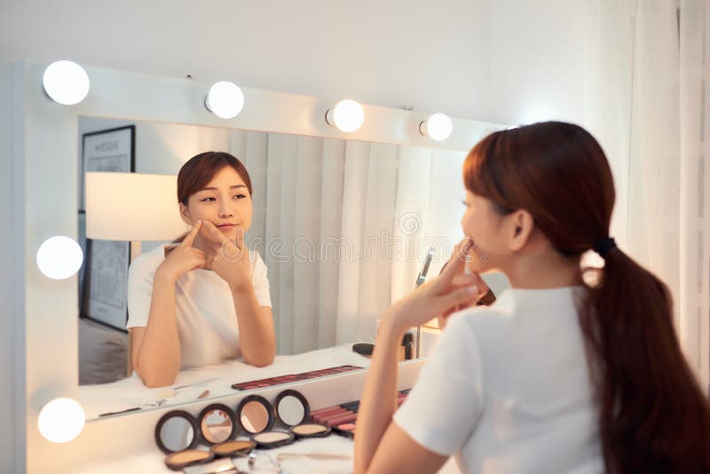 Young Asian Woman Touching Skin Face In Front Of Mirror Stock Image