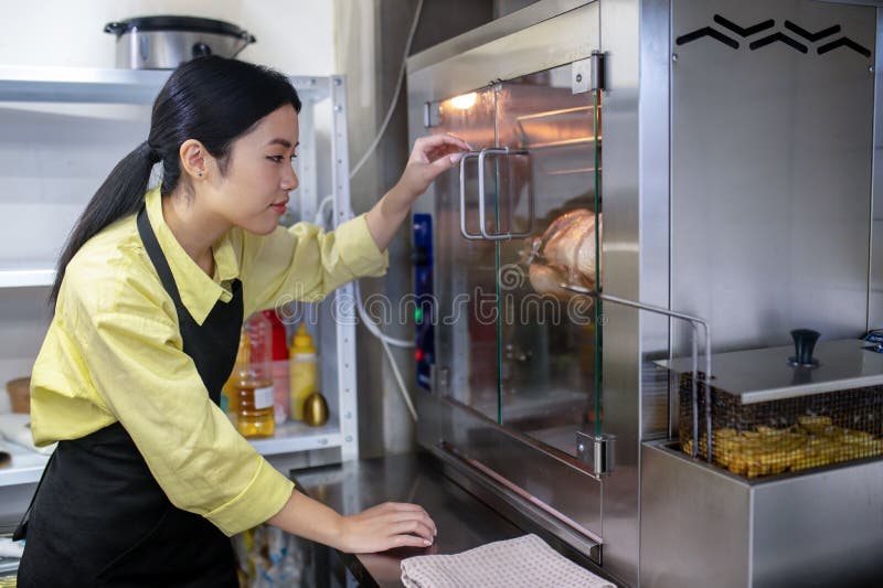 Young Asian Woman Working in the Kitchen and Regulating Ovens ...