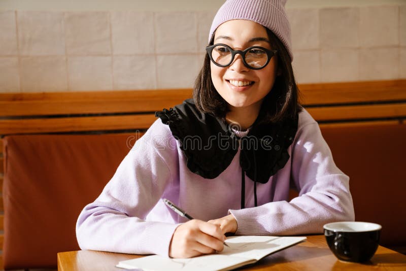 Young Asian Woman Writing Down Notes while Drinking Coffee Stock Photo ...