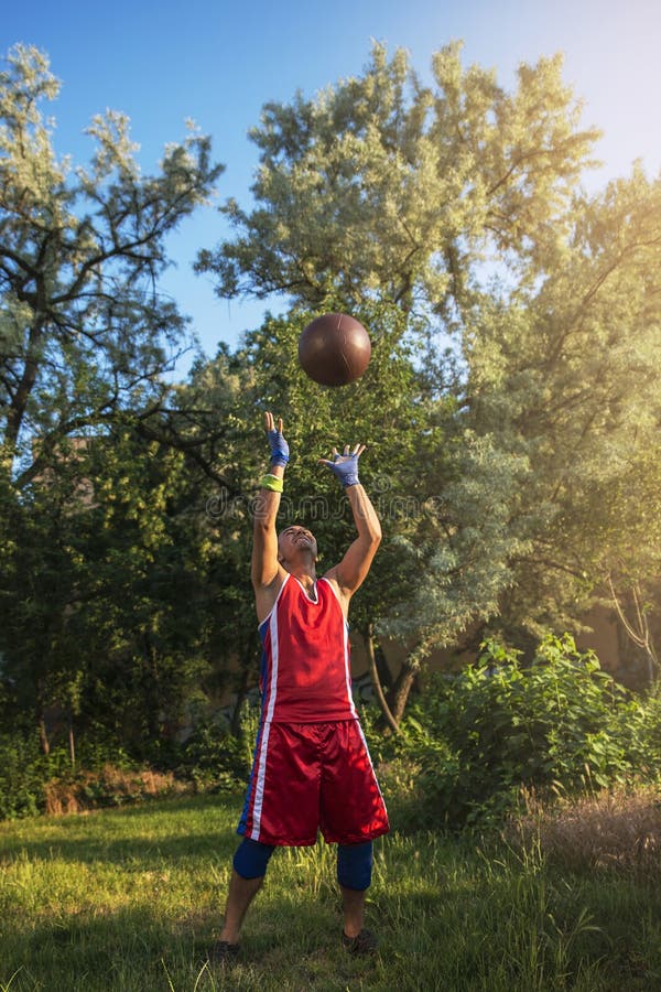 Young Athlete Performs Sports Exercises with a Ball Outdoors. Stock ...