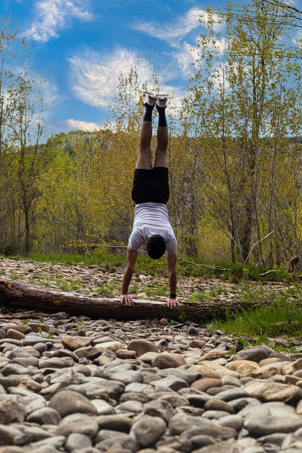 Young Man in Sportswear and Shorts Climbing on a Fallen Tree Trunk ...