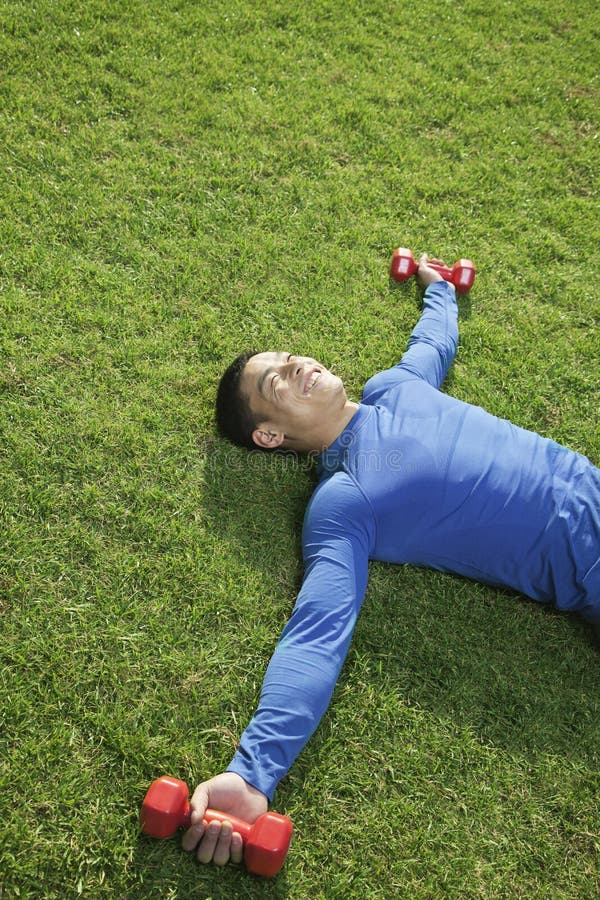 Young Athletic Man Lying Down in Grass with Dumbbells, Directly Above ...